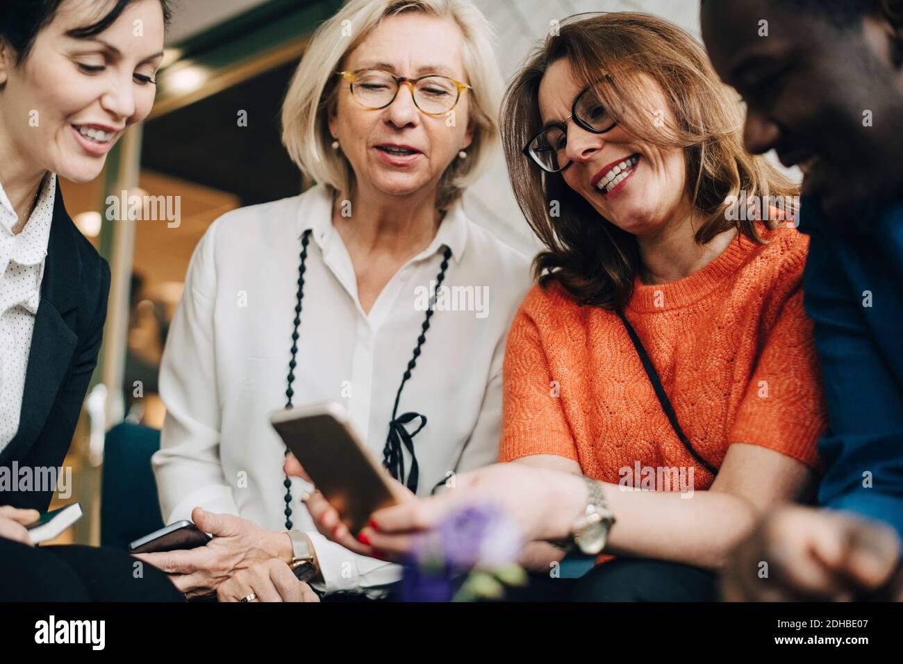 Business people looking at mobile phones while sitting together in ...