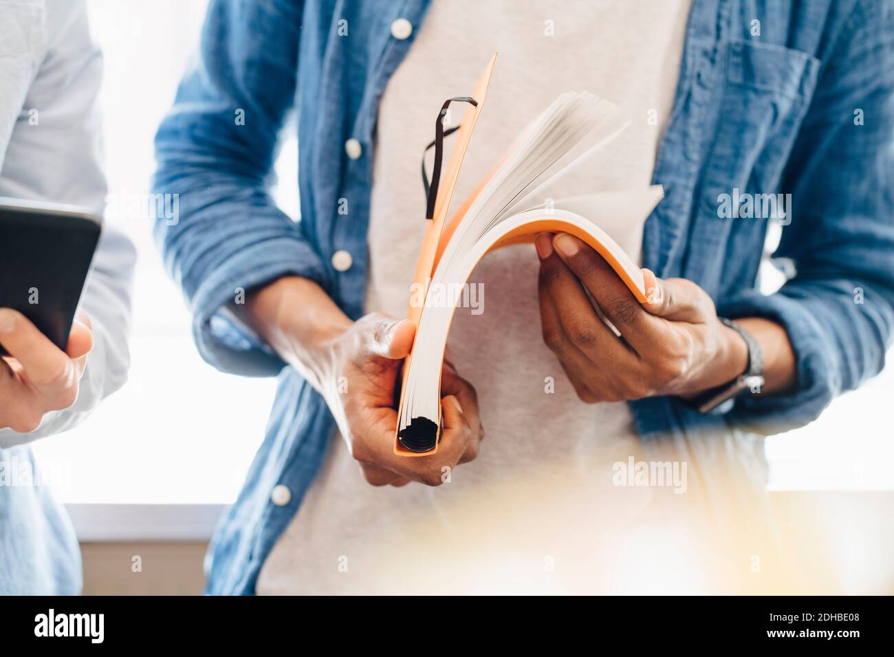 Midsection of computer programmers with book and digital tablet ...