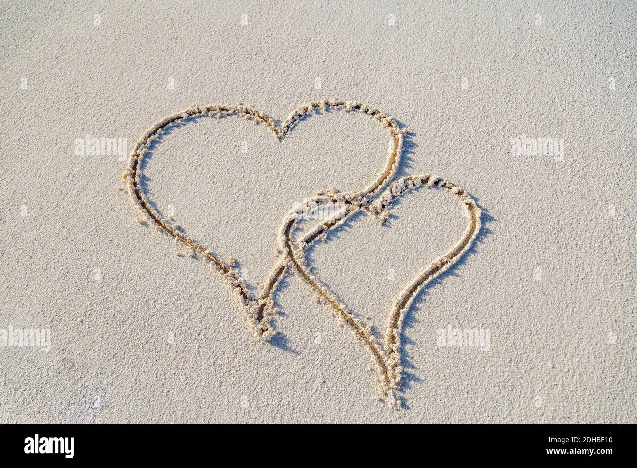 Hearts symbol on a sand of beach with soft blue wave on background. A ...