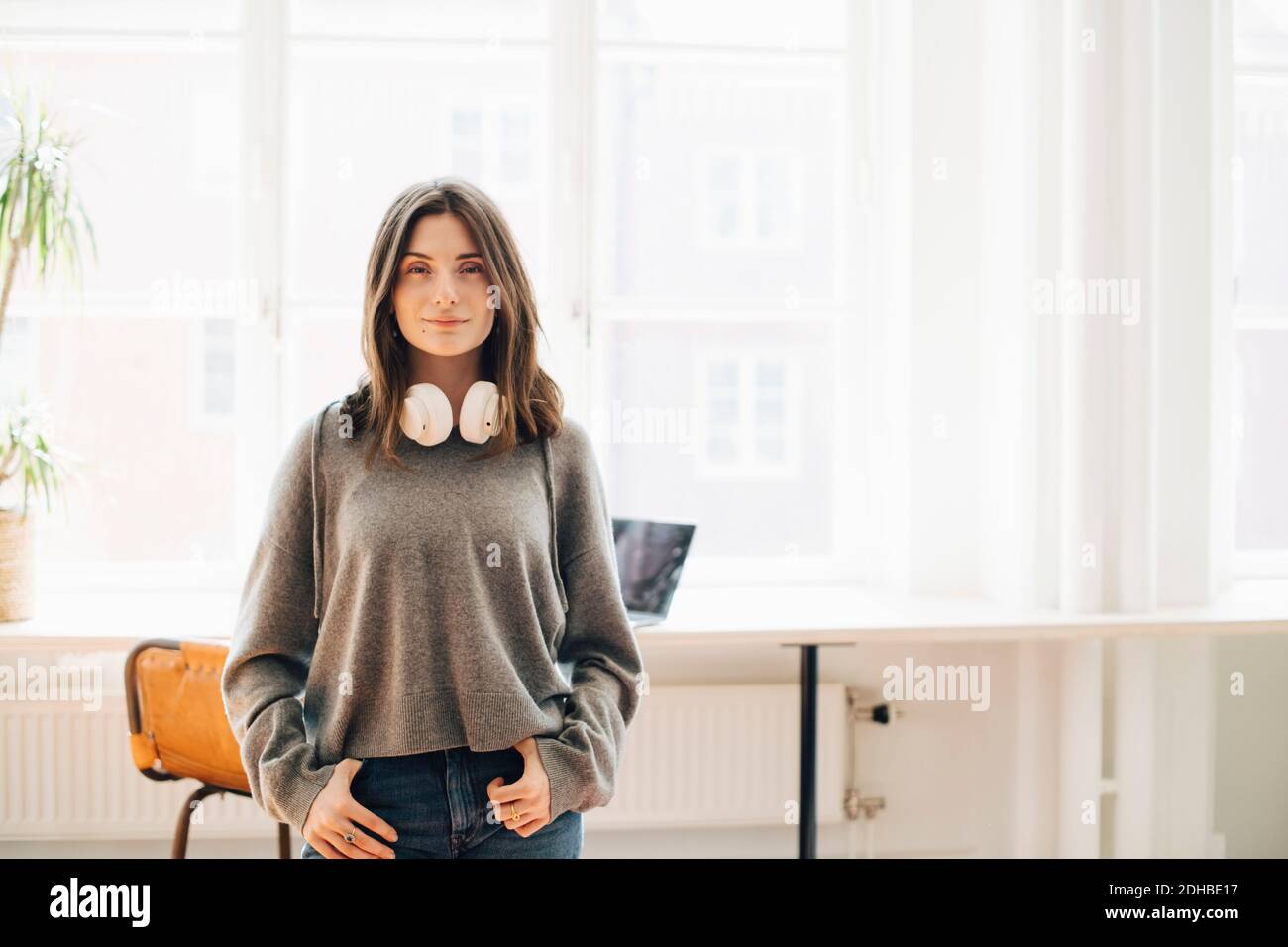 Portrait of female computer programmer with headphone standing against ...