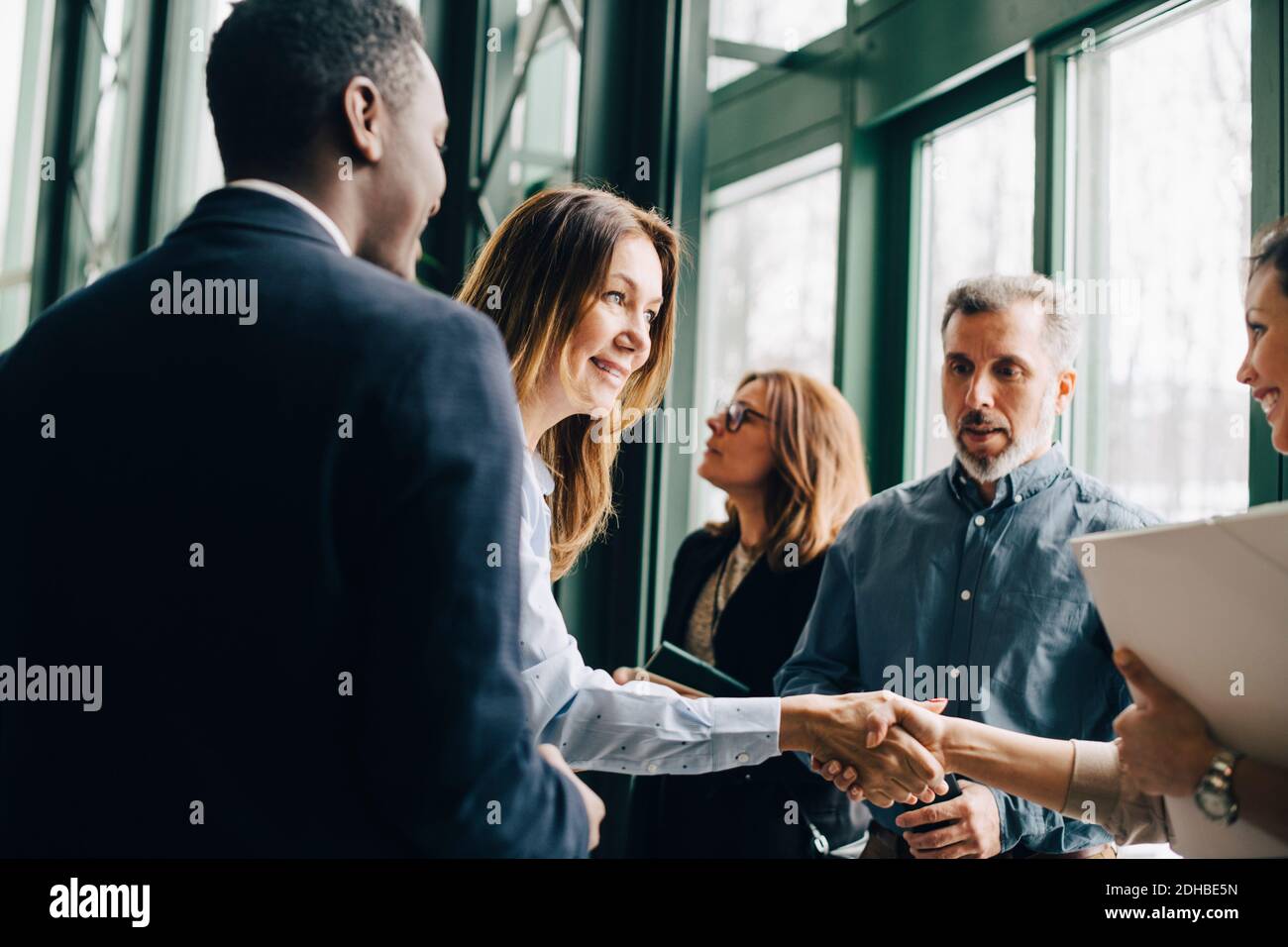 Mature businesswoman greeting colleagues in meeting at office Stock ...