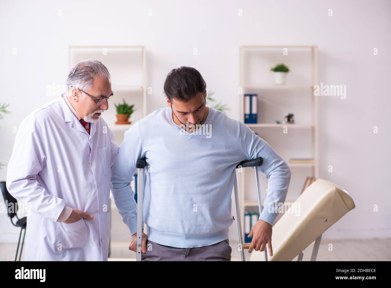 Young leg injured man visiting old doctor osteopath Stock Photo - Alamy