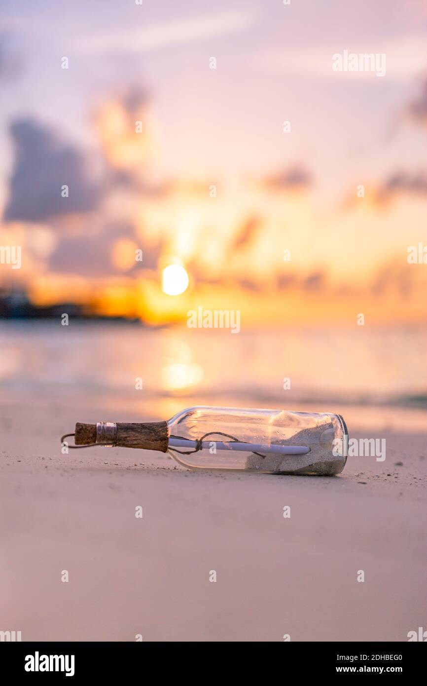 Message in the bottle washed ashore against the sun setting down ...