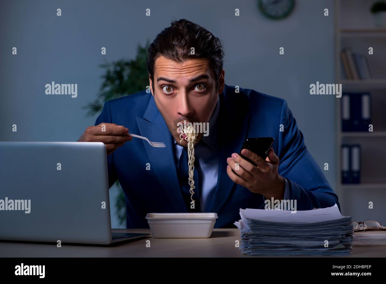 Hungry employee working late in the office Stock Photo - Alamy