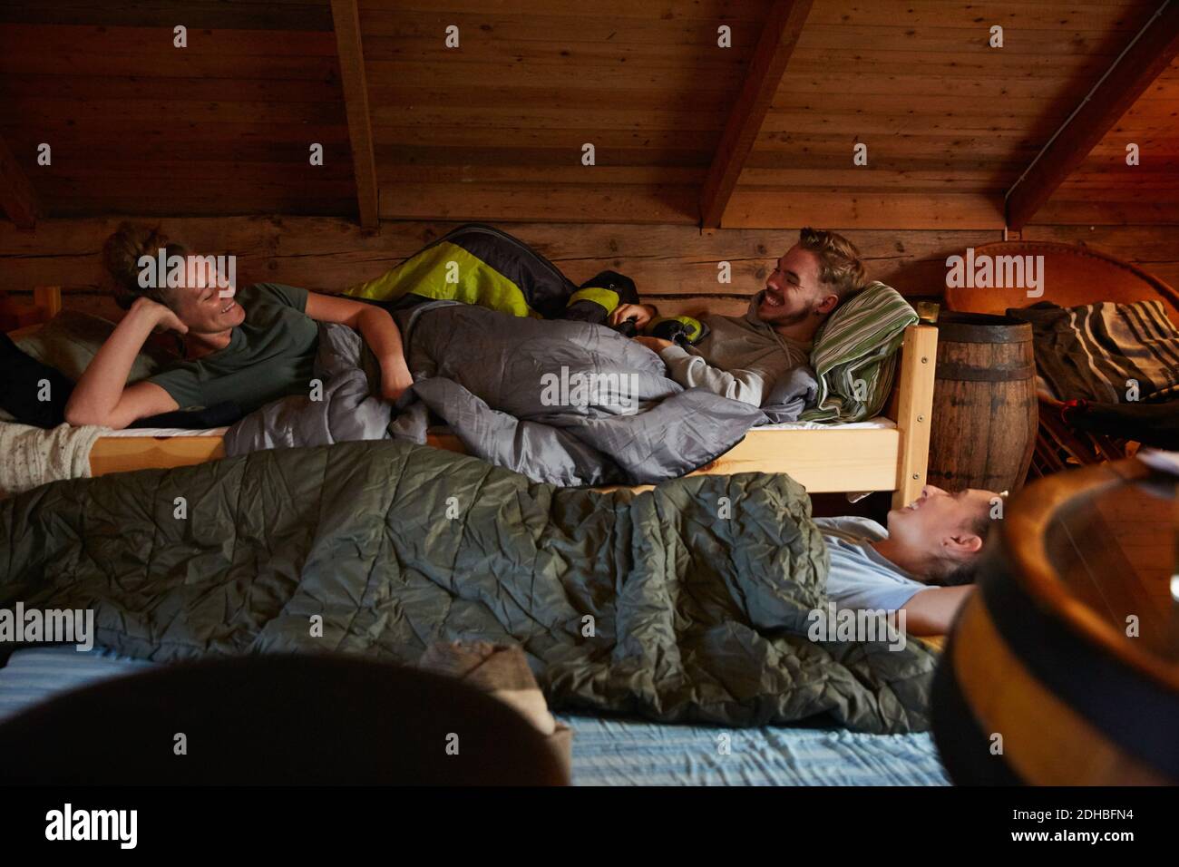 Smiling friends talking while resting in log cabin during bedtime Stock ...