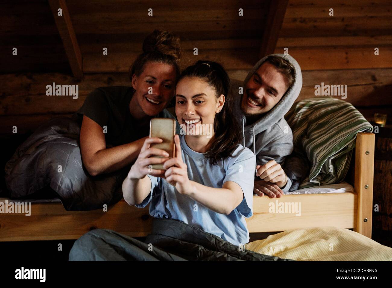 Smiling young woman taking selfie with enjoying with friends in cottage ...