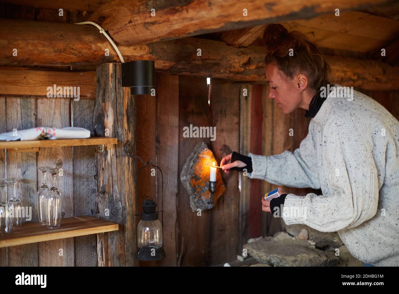 Side view of mid adult woman lighting candle in cottage Stock Photo - Alamy