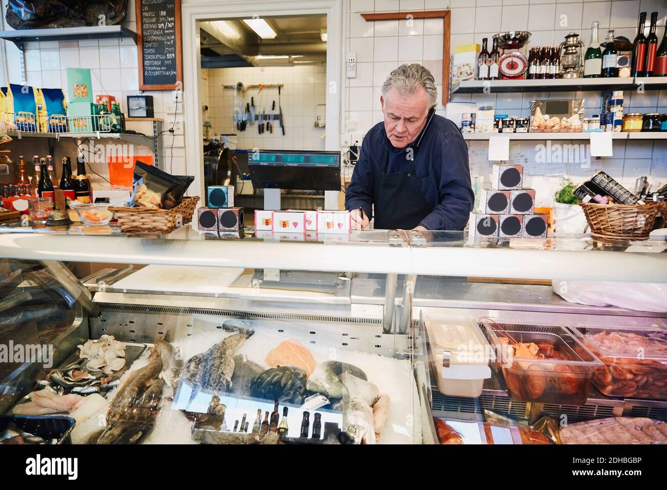 Male owner taking order though mobile phone at counter in store Stock ...