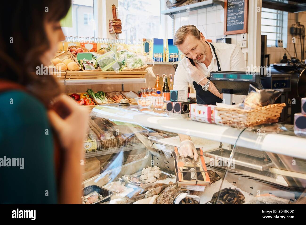 Male owner talking on mobile phone while picking up product from ...