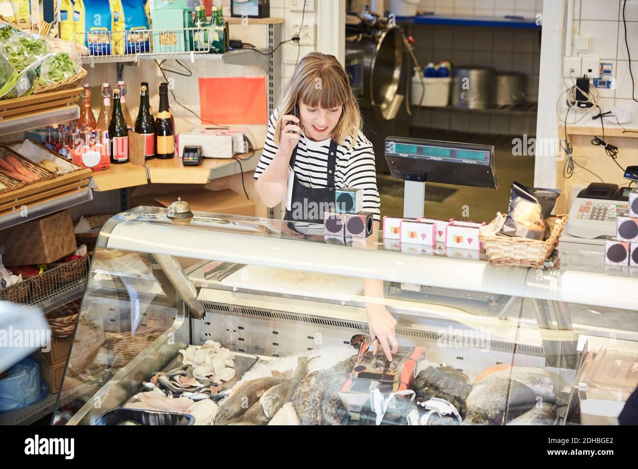 Female owner using mobile phone while working at counter in store Stock ...