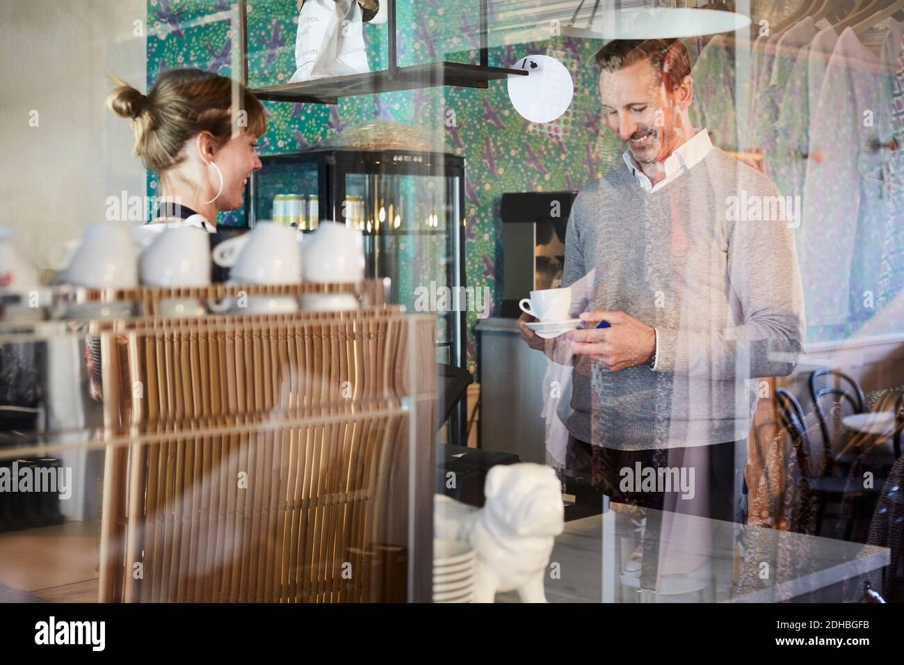 Owner looking at customer having coffee at checkout counter seen ...