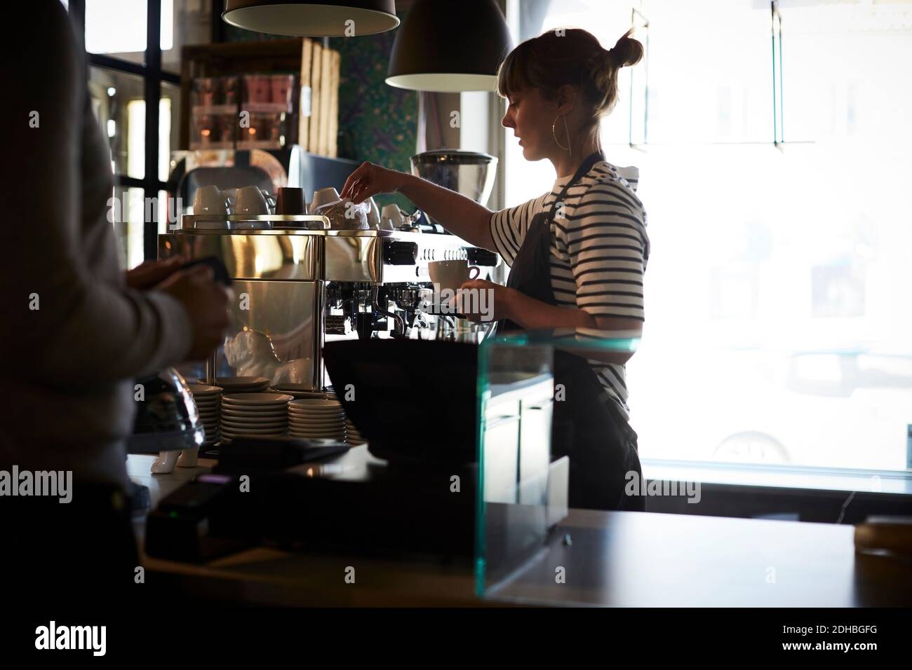 Female barista preparing coffee while customer standing at checkout ...