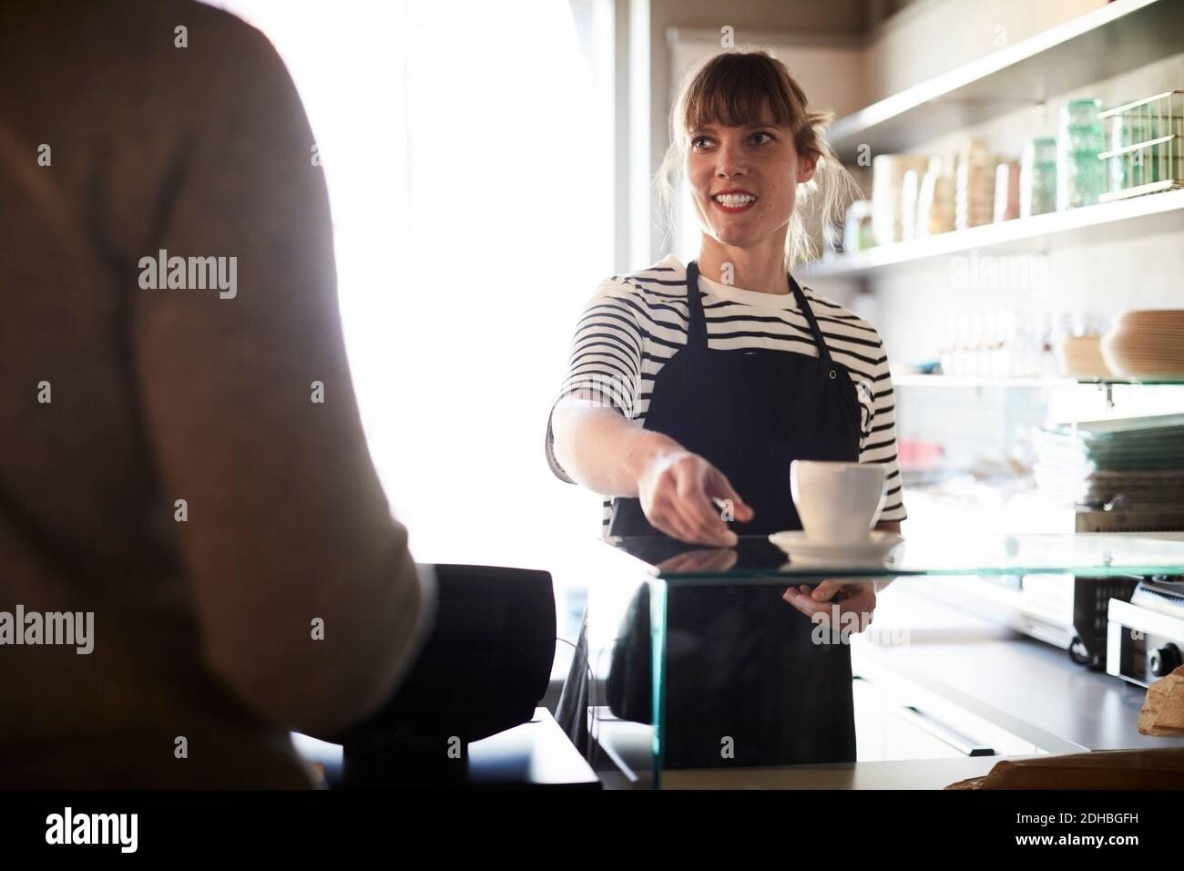 Smiling female barista serving coffee to male customer at cafe Stock ...