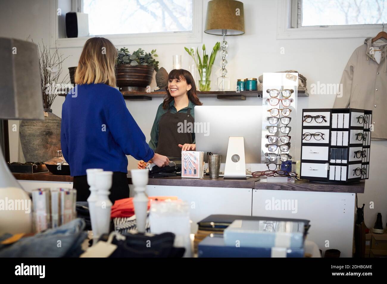 Smiling owner talking to female customer while receiving payment at ...