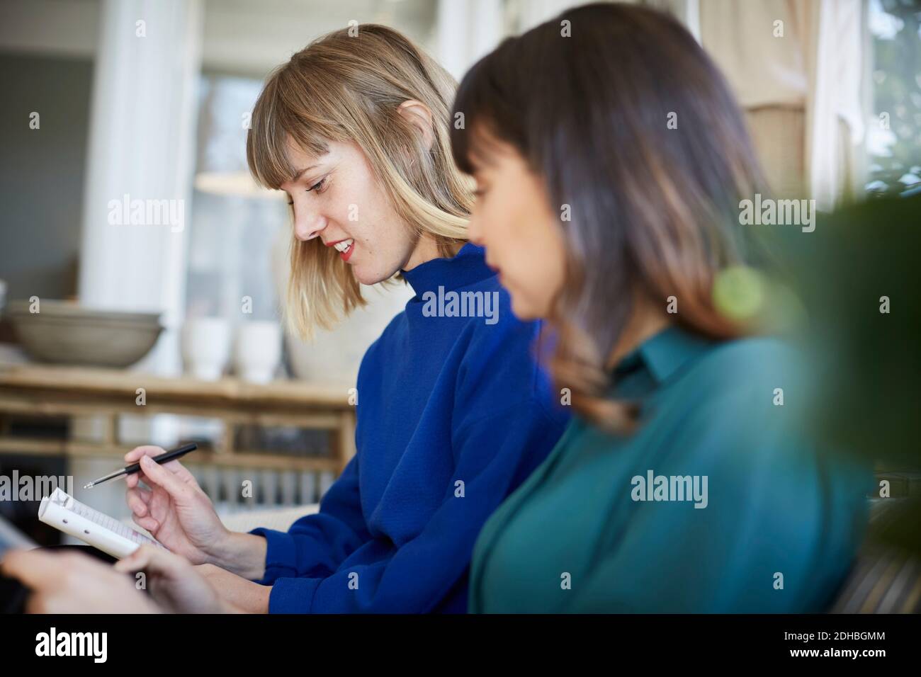 Side view of female partners communicating in store Stock Photo - Alamy