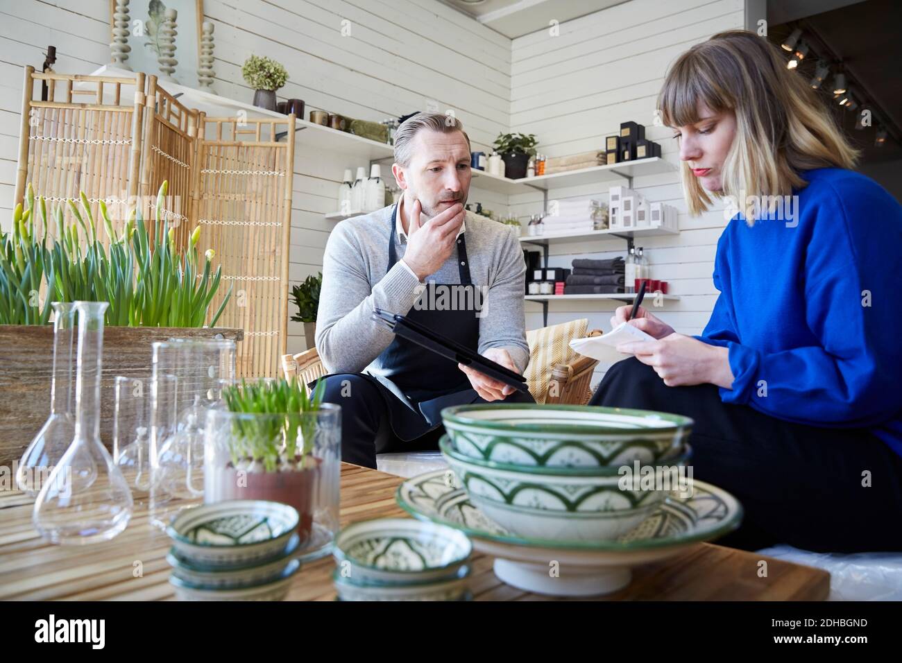 Male and female partners discussing over merchandise at store Stock ...