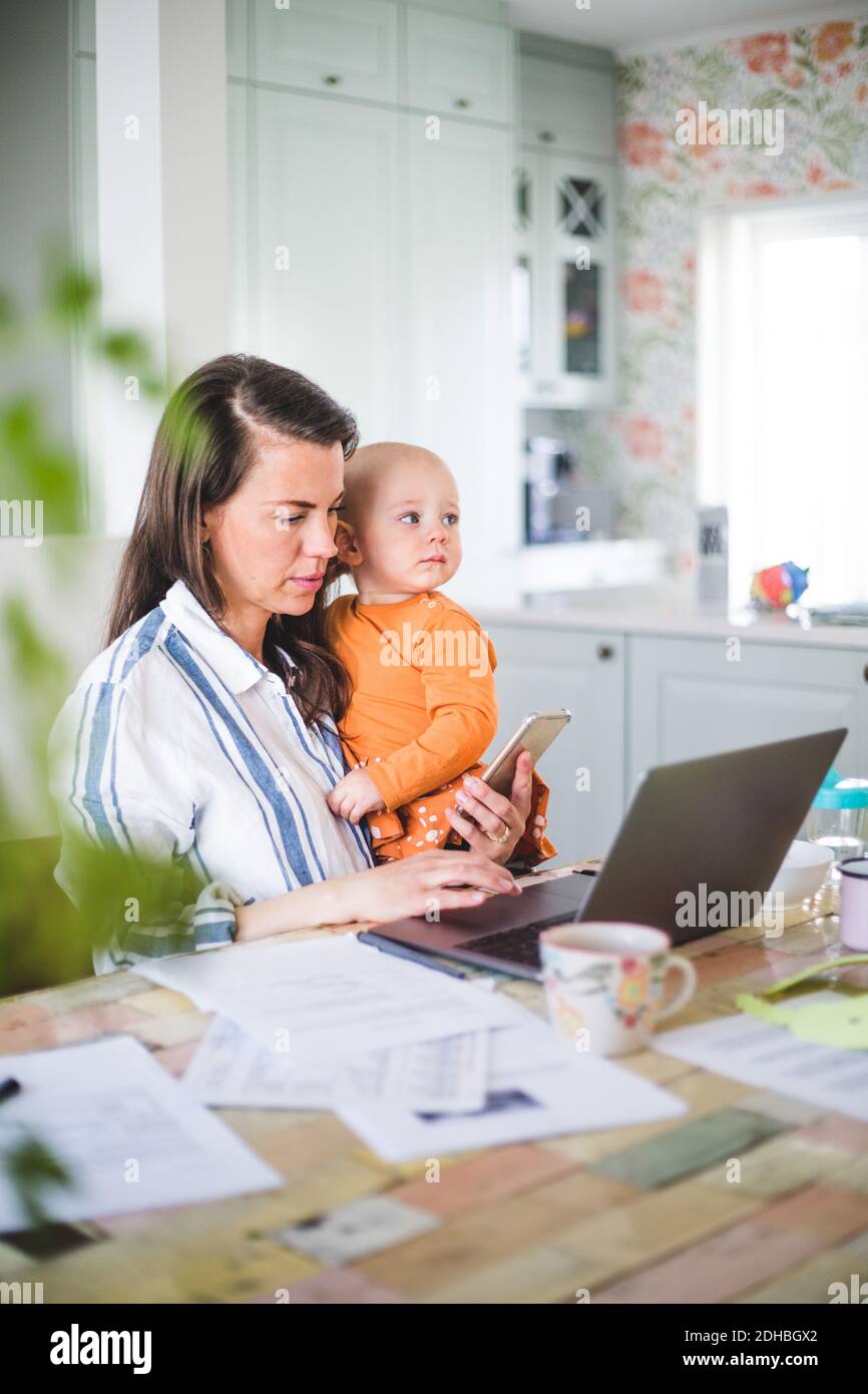 Busy female parent running business while taking daughter's care at ...