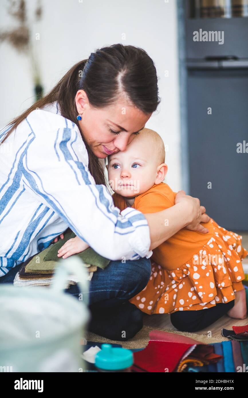 Multi-tasking fashion designer embracing loving daughter at home Stock ...