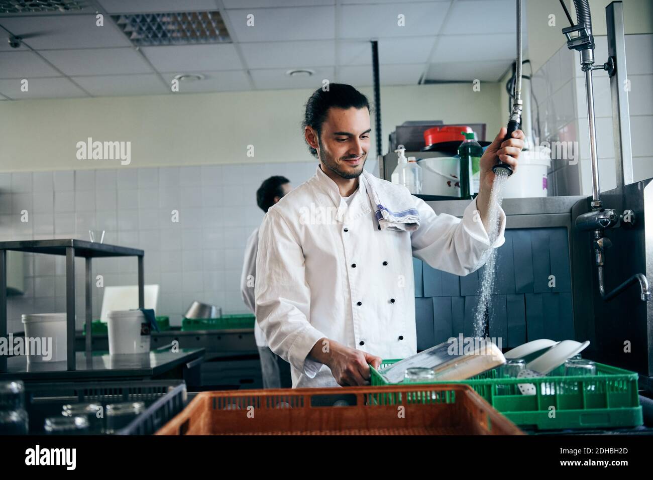 Young chef spraying water on plates in commercial kitchen Stock Photo ...
