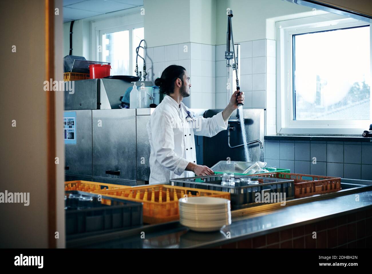 Chef looking at window while washing dishes in kitchen Stock Photo - Alamy