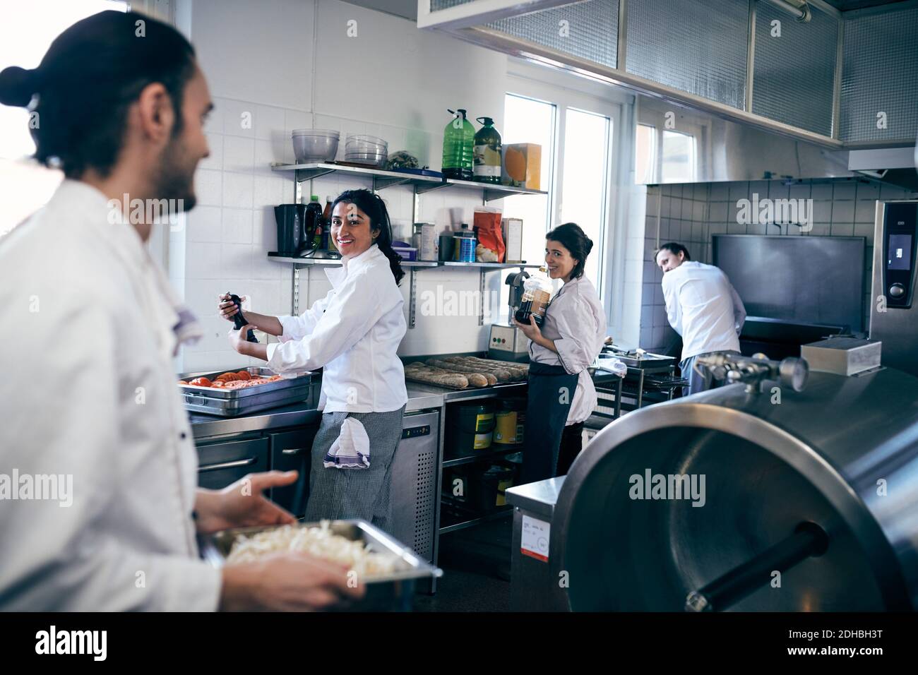 Happy chefs looking at colleague in commercial kitchen Stock Photo - Alamy