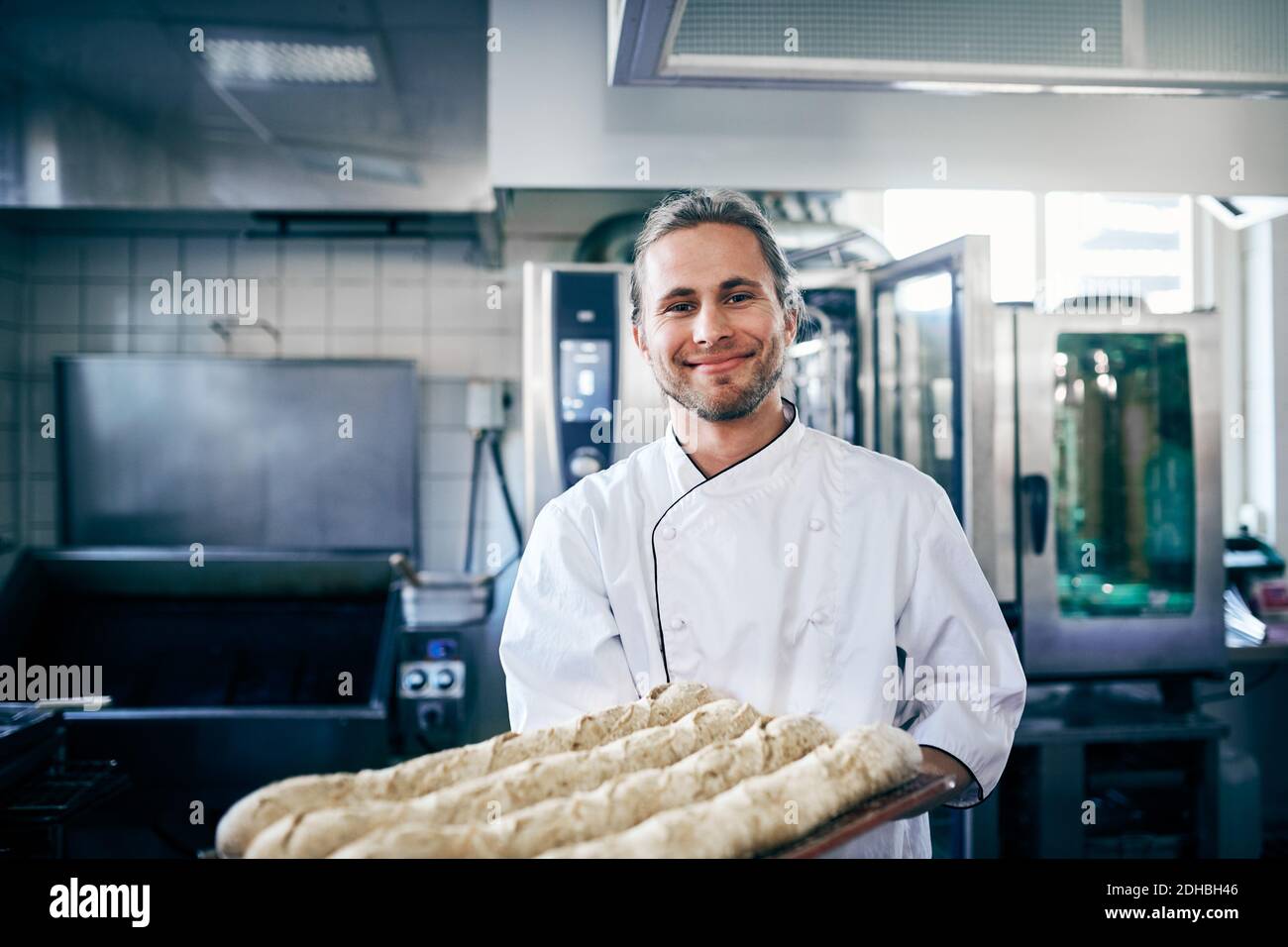 Portrait of confident chef baking breads in commercial kitchen Stock ...
