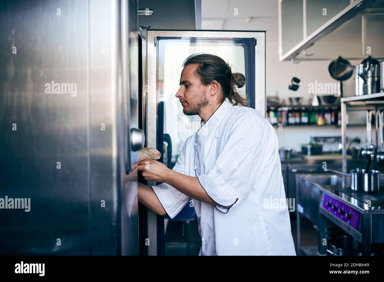 Male chef putting bread in oven at commercial kitchen Stock Photo - Alamy