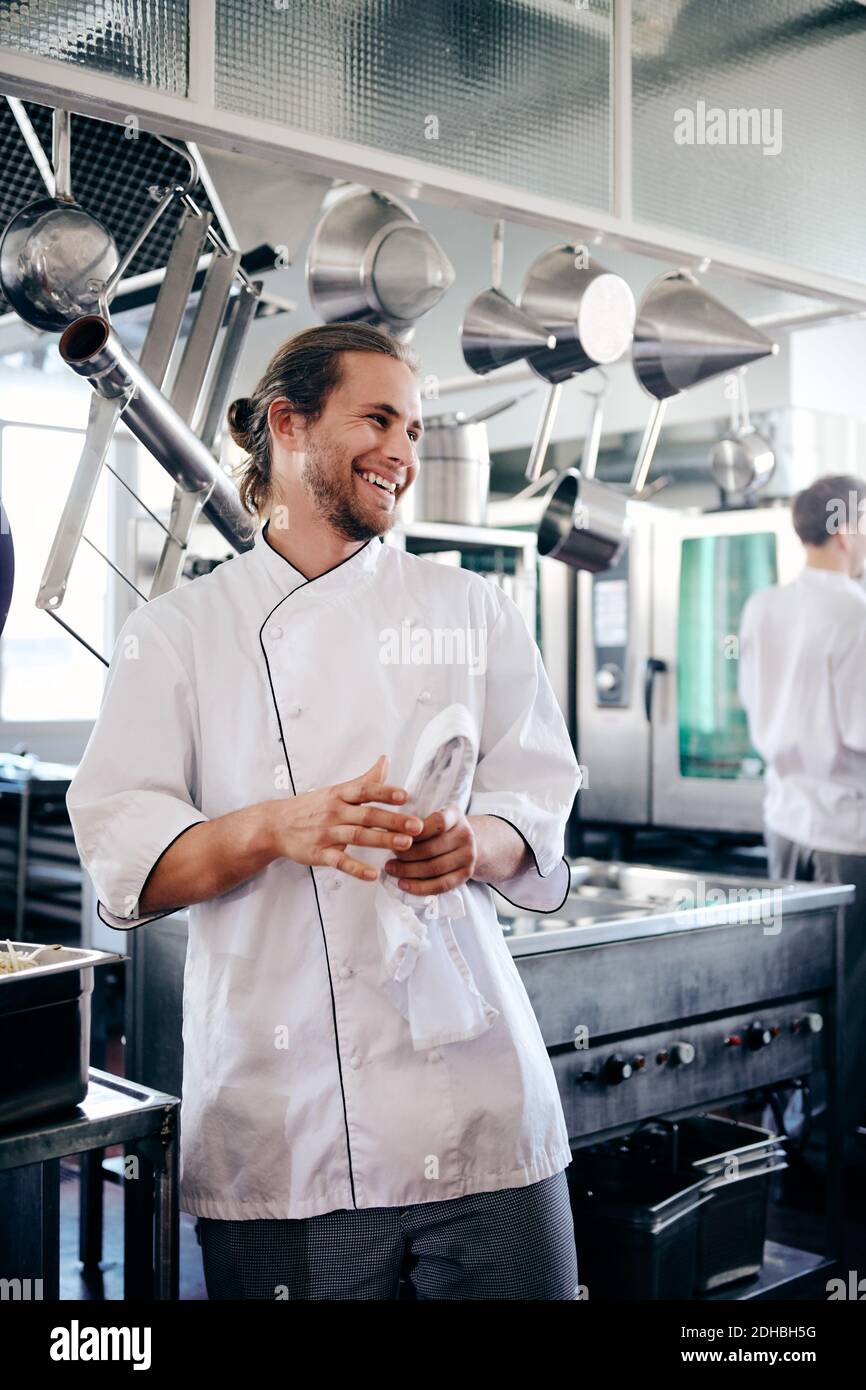 Smiling male chef holding napkin in commercial kitchen Stock Photo - Alamy