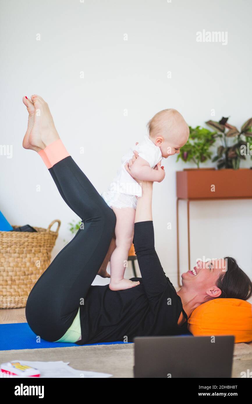 Side view of cheerful mother playing with daughter while lying in home ...