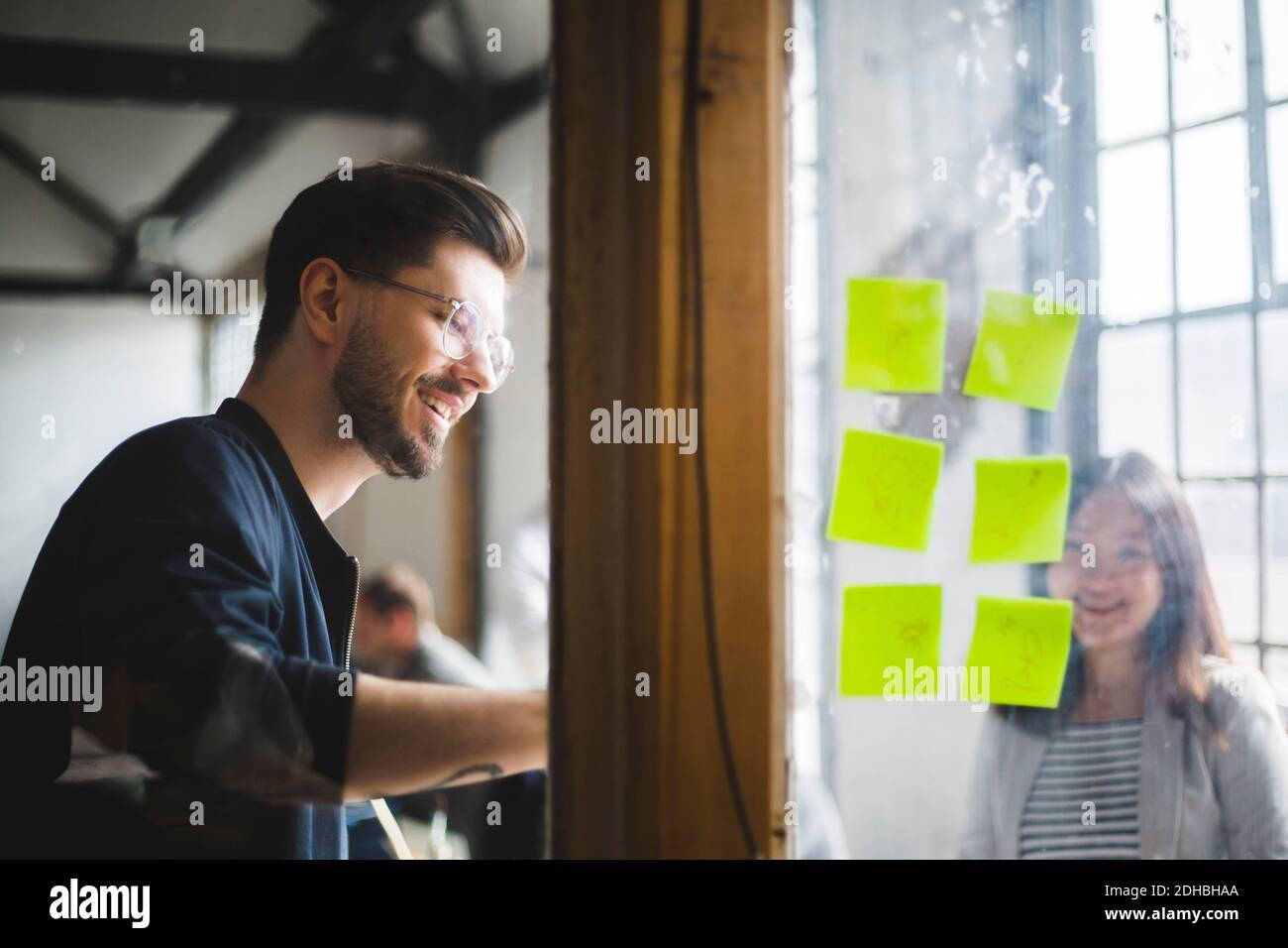 Smiling computer programmers having meeting in board room seen through glass at new creative ...
