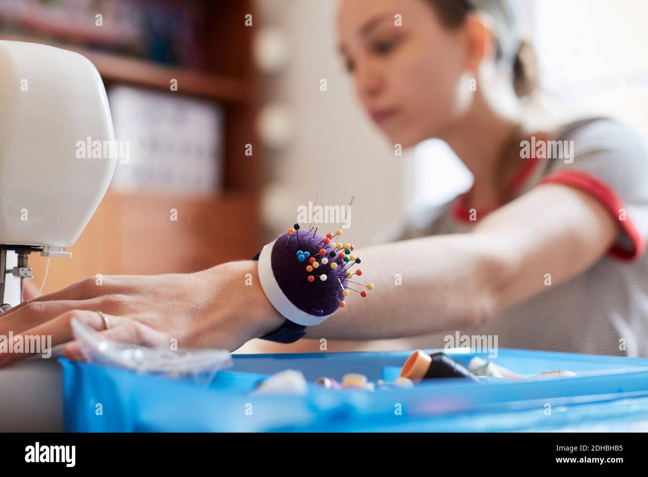 Close up of female tailor wearing pin cushion on wrist while using ...