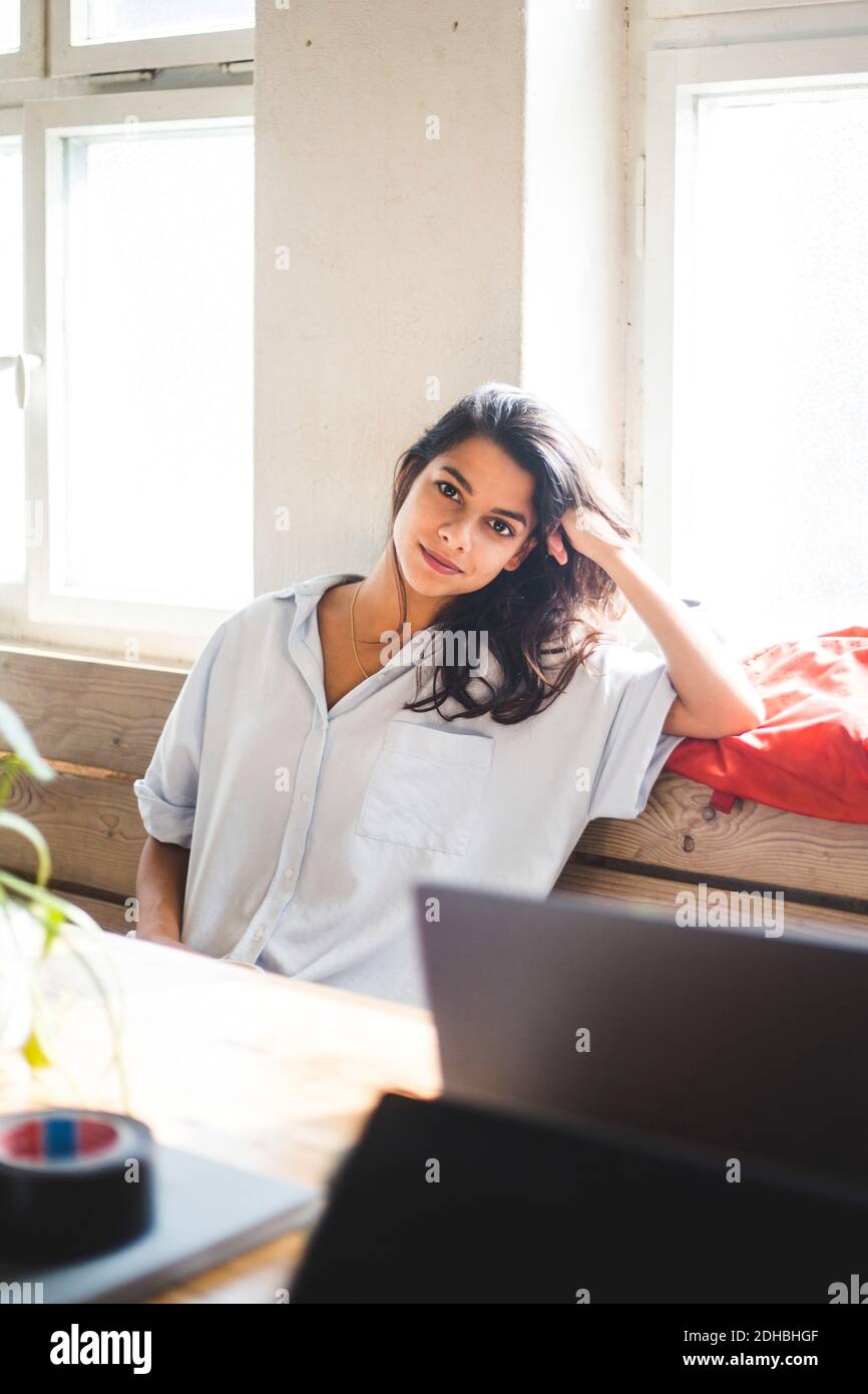 Portrait of young female computer programmer sitting in creative office ...