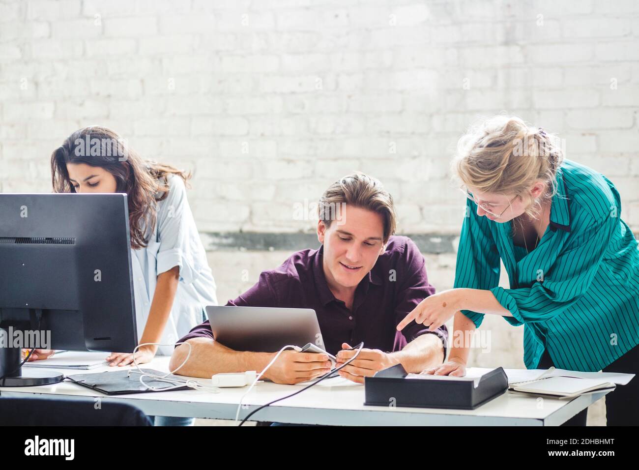 Male computer programmer connecting cable while discussing with female ...