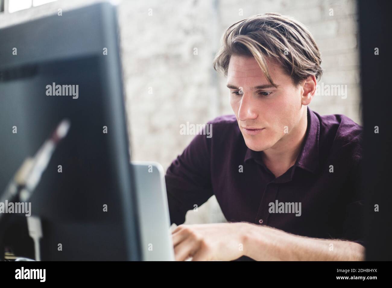 Male computer programmer using laptop while working in office Stock ...