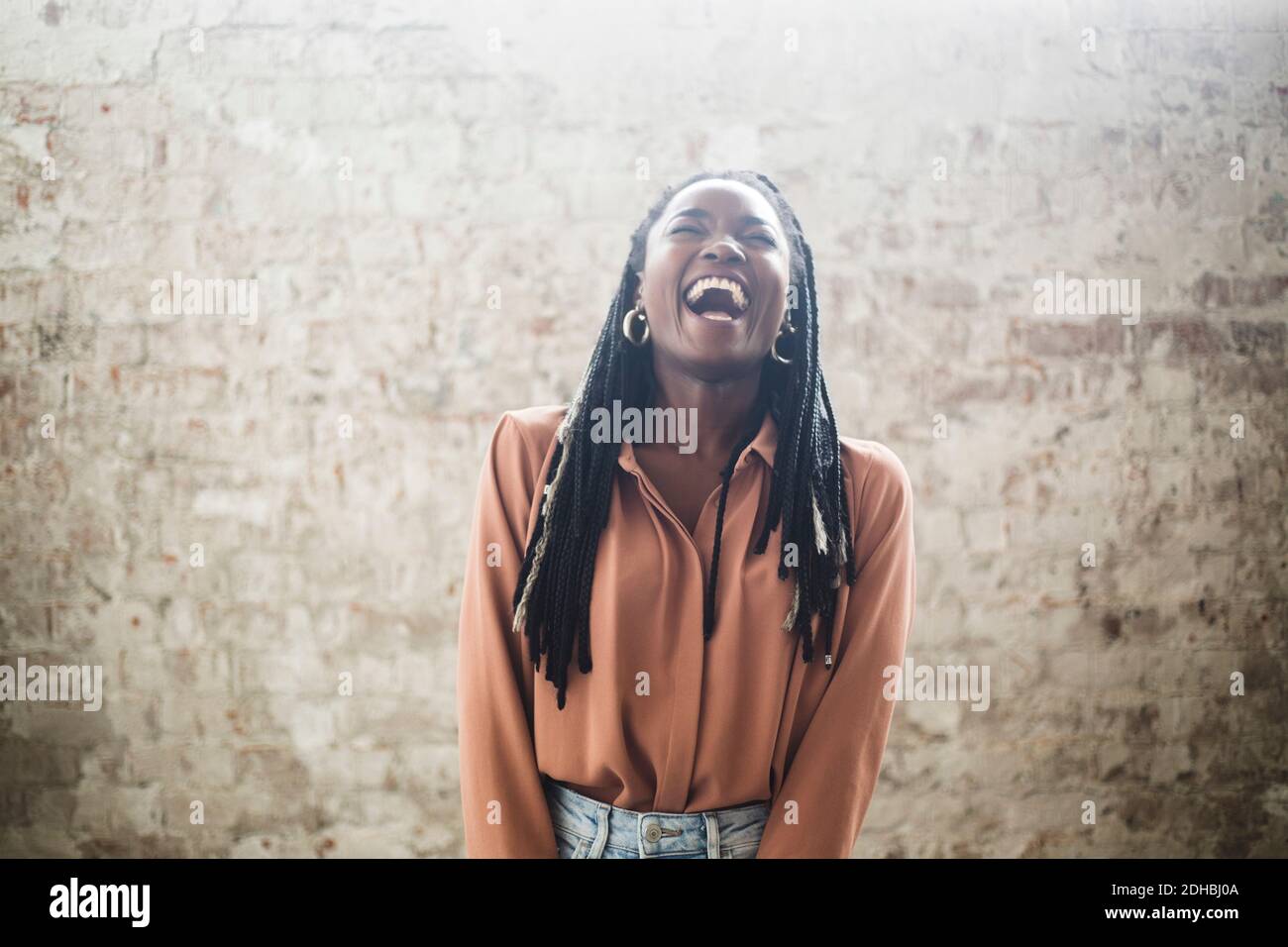 Female computer hacker with dreadlocks laughing against wall in office ...