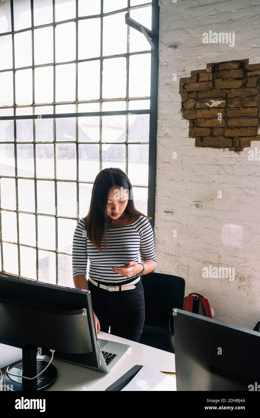 Confident female computer programmer using technologies standing by ...