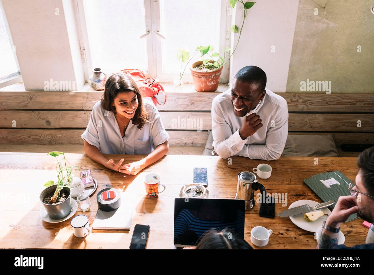 High angle view of smiling programmers discussing at table in creative ...