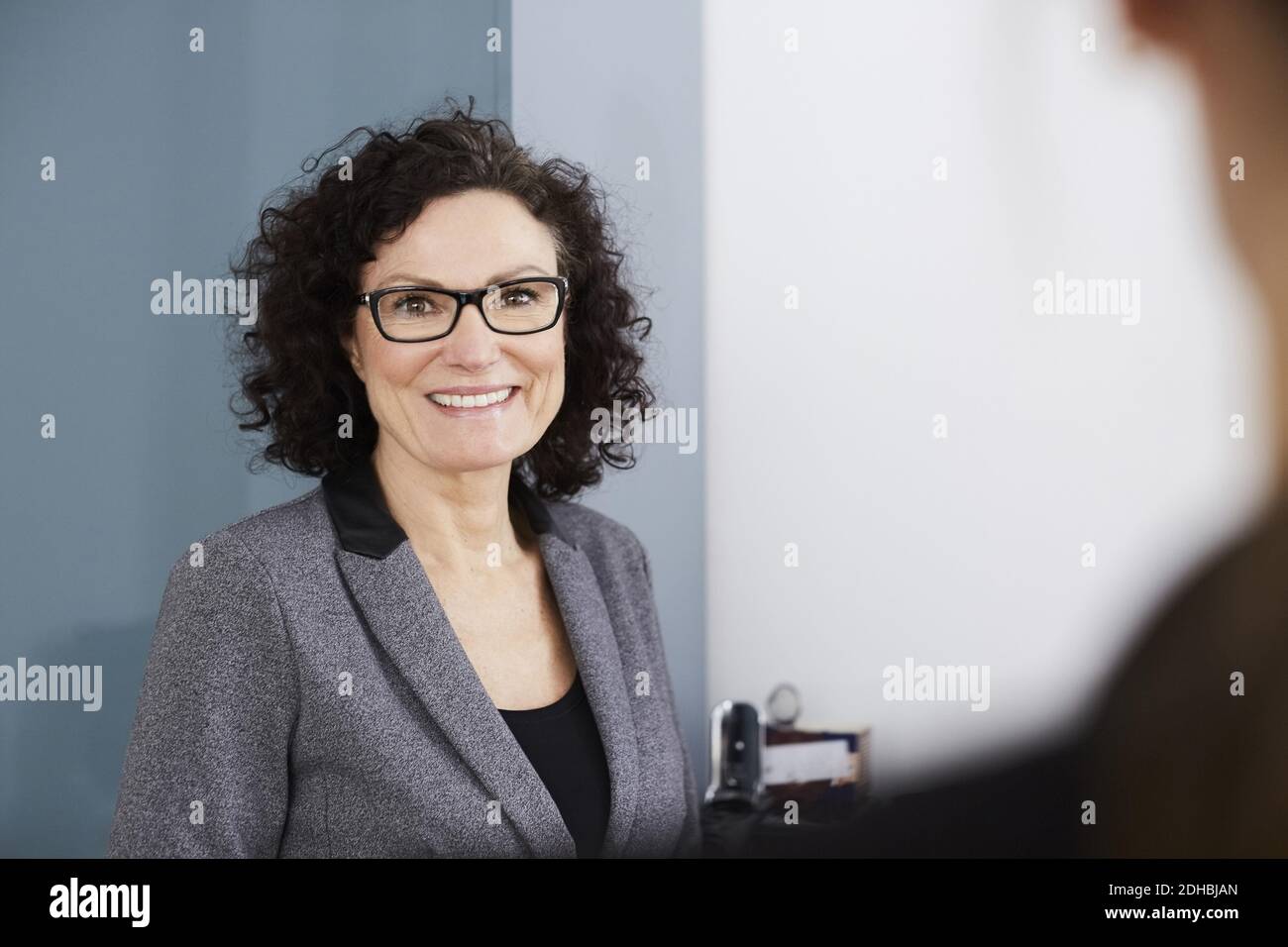 Portrait of smiling confident businesswoman wearing eyeglasses at ...