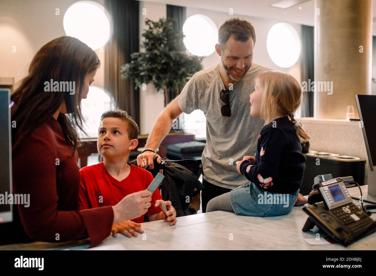 Smiling parents talking to children at reception in hotel Stock Photo ...