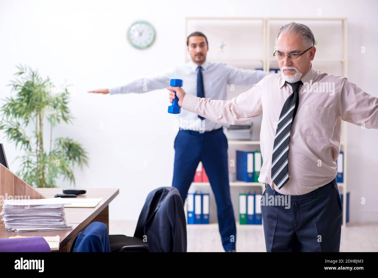 Two employees doing physical exercises at workplace Stock Photo - Alamy