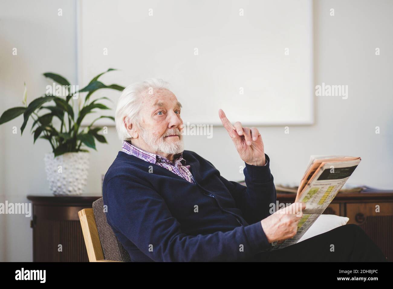 Senior man pointing while holding newspaper in nursing home Stock Photo ...