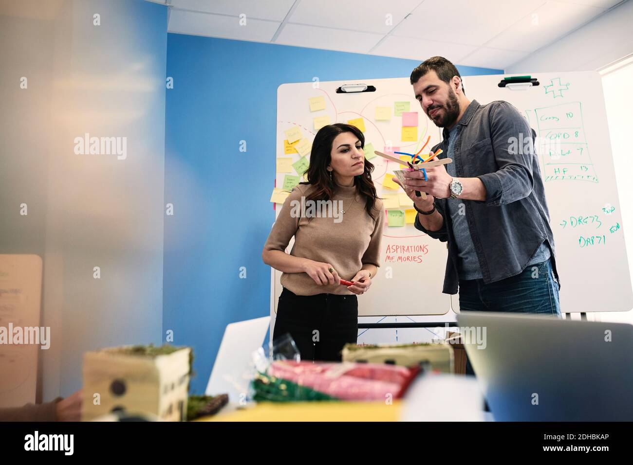 Male and female engineers discussing over project at table in office ...