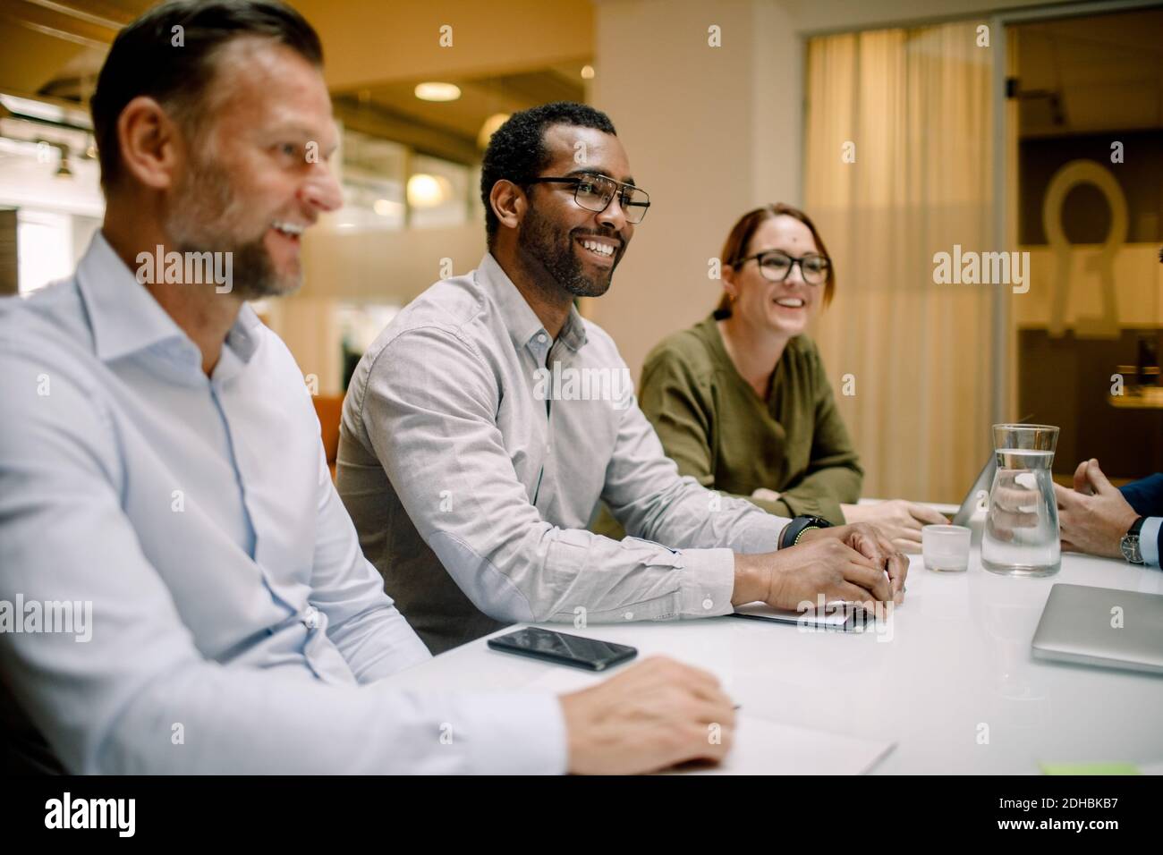 Sales executives smiling during business meeting at conference table in ...