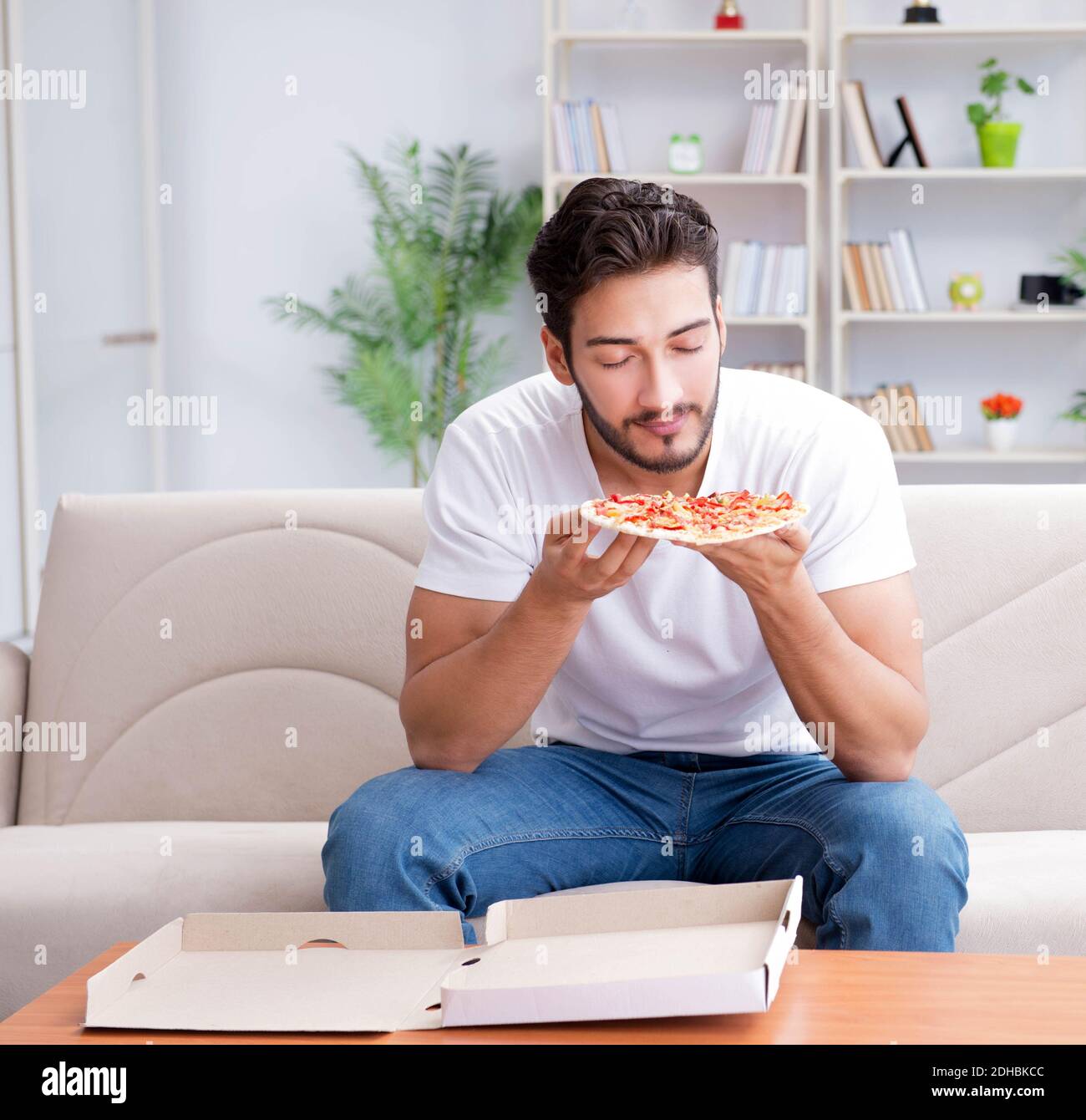 Man eating pizza having a takeaway at home relaxing resting Stock Photo ...