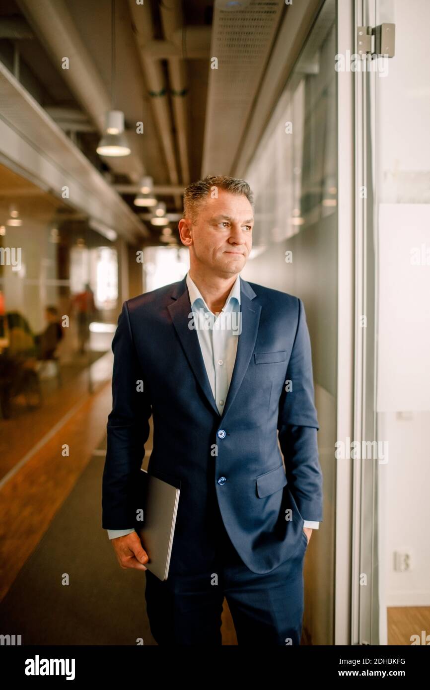 Thoughtful well-dressed mature sales manager looking away while ...