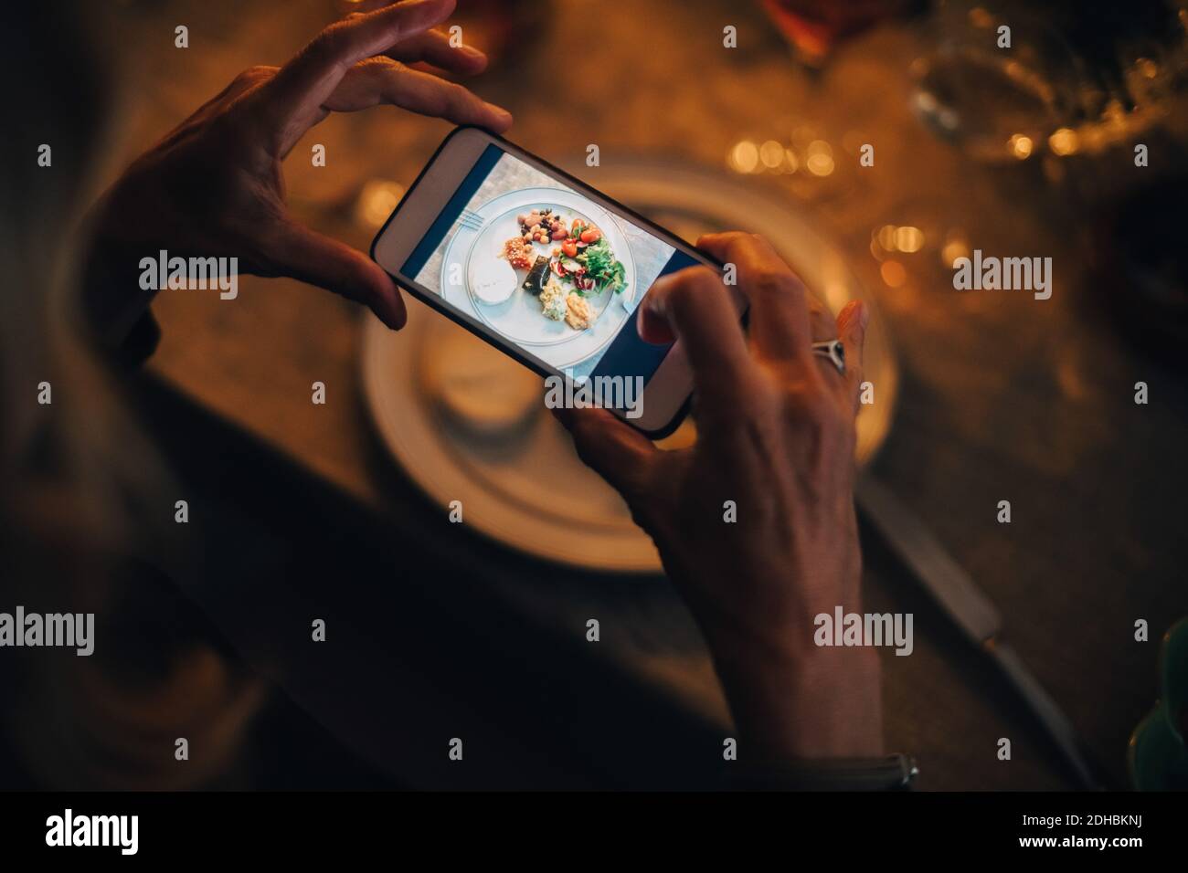 High angle view of mature woman photographing food at dining table in ...