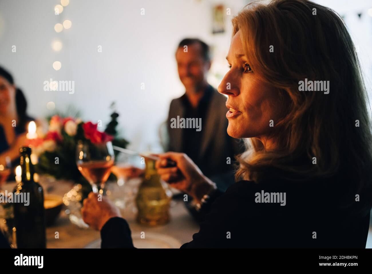 Close-up of woman raising toast with wineglass during dinner party ...