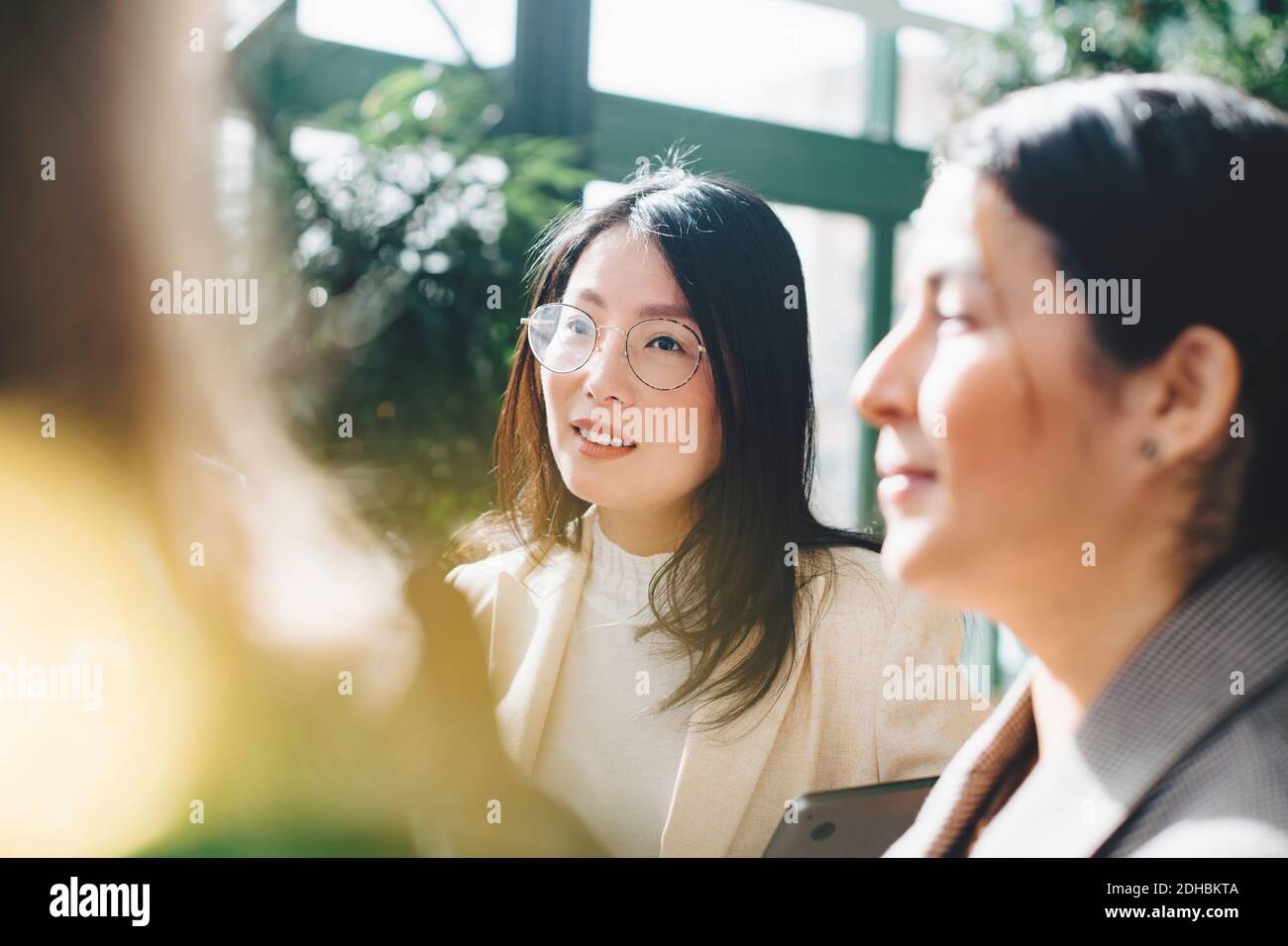 Female professional discussing with coworkers at conference meeting ...