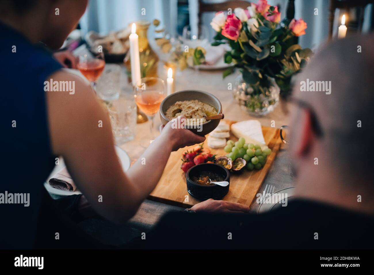 Woman serving food to male man at dining table in dinner party Stock ...