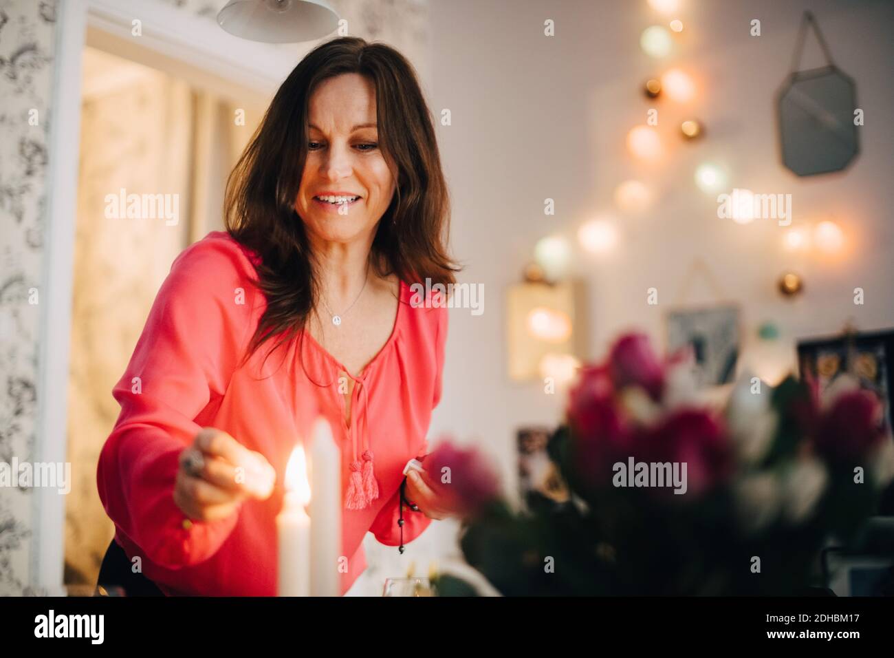 Happy mature woman igniting candle in party at home Stock Photo - Alamy